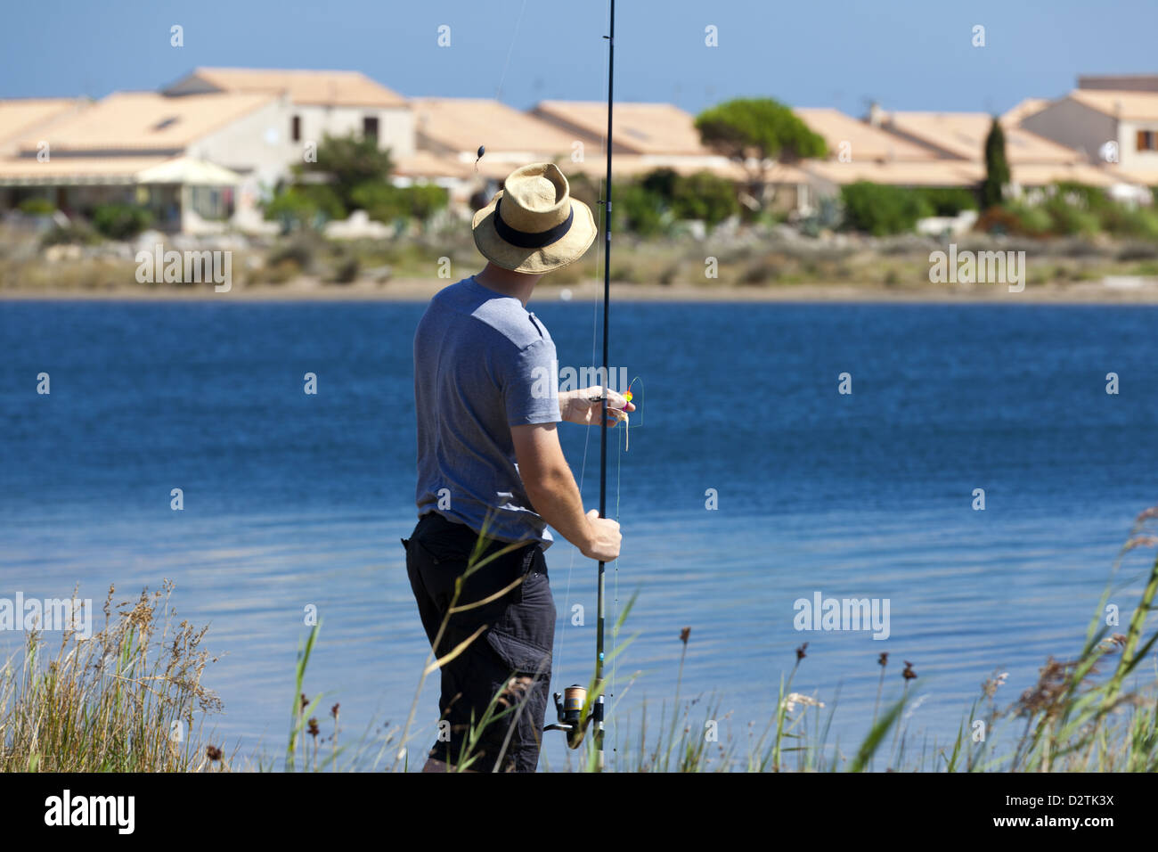 An angler stands on the shore in the bay in the resort in southern ...