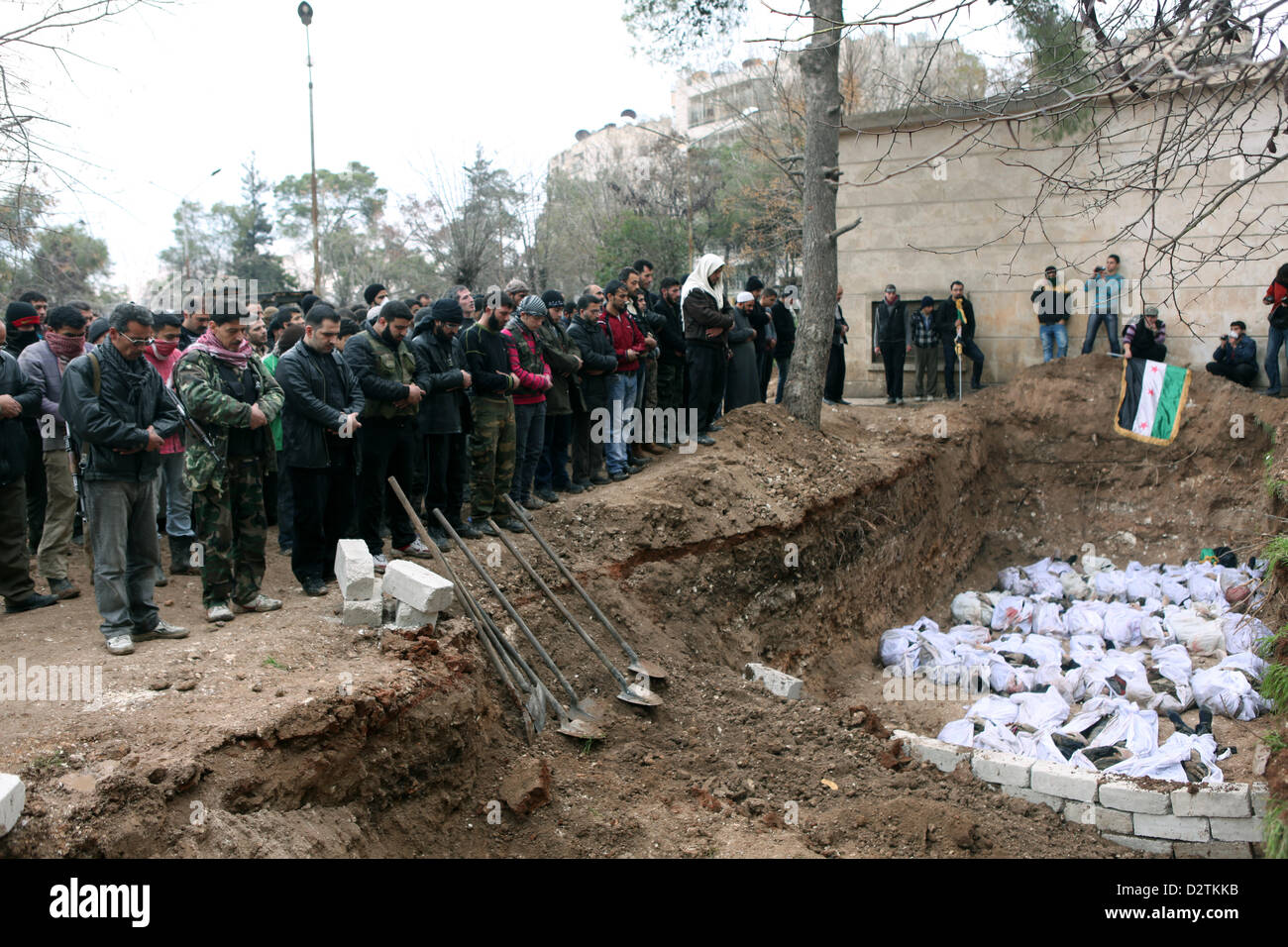 Unidentified victims covered in white cloths are being buried in a ...