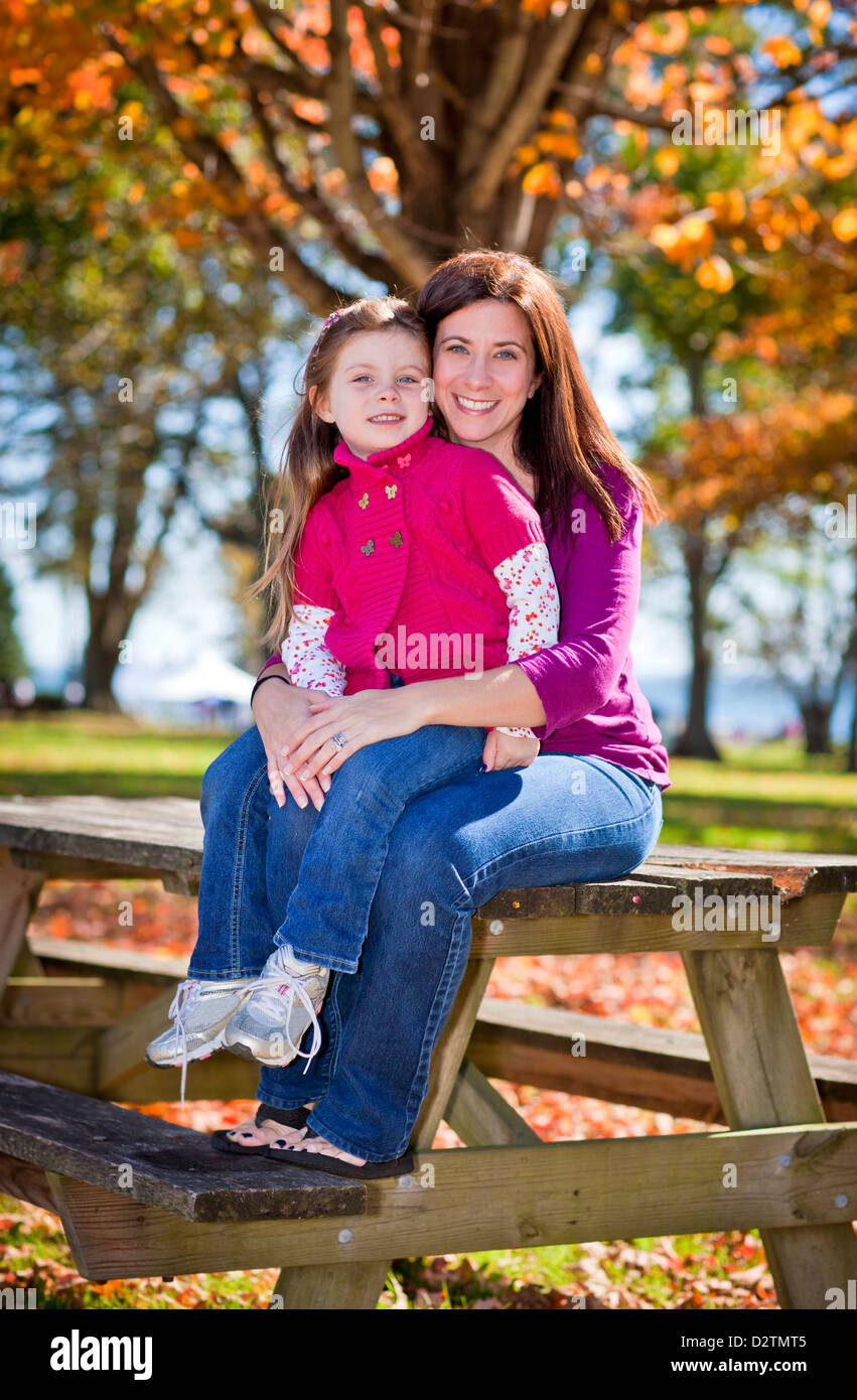 Mother and daughter sitting on a bench in the fall Stock Photo - Alamy