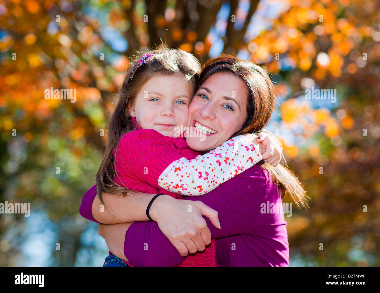Beautiful mother and daughter hugging against fall background Stock ...