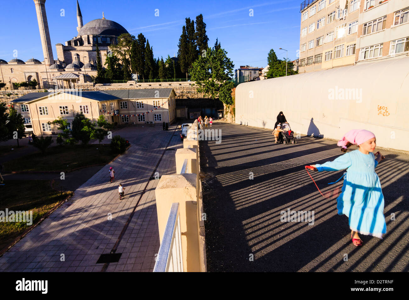 Turkish girl playing jump rope at a park with mosque in background ...