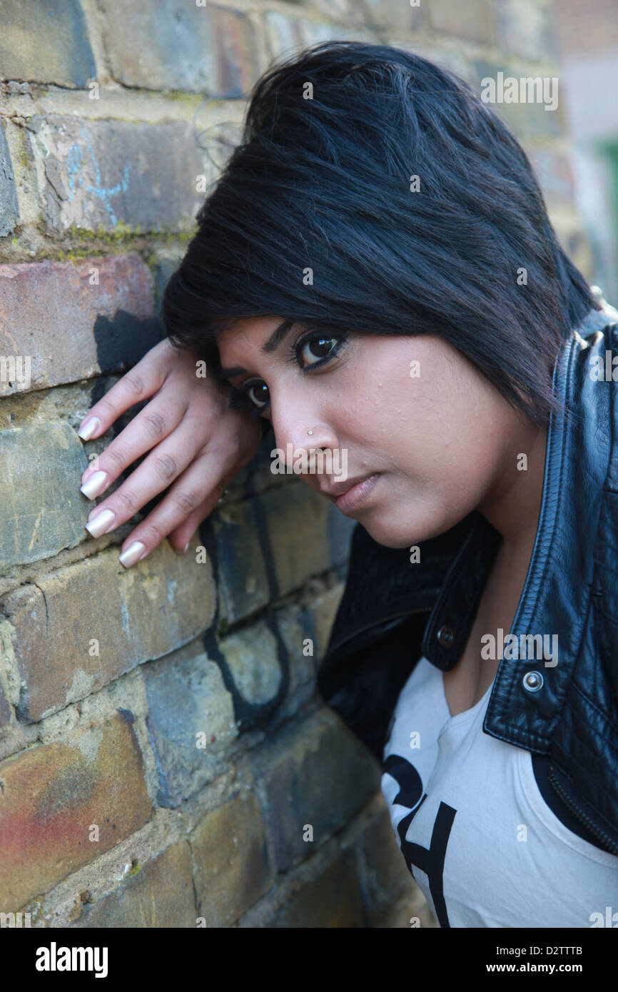 Upset and scared Asian girl leaning against a brick wall Stock Photo ...