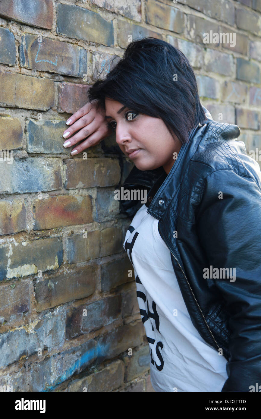 Upset and scared Asian girl leaning against a brick wall Stock Photo ...
