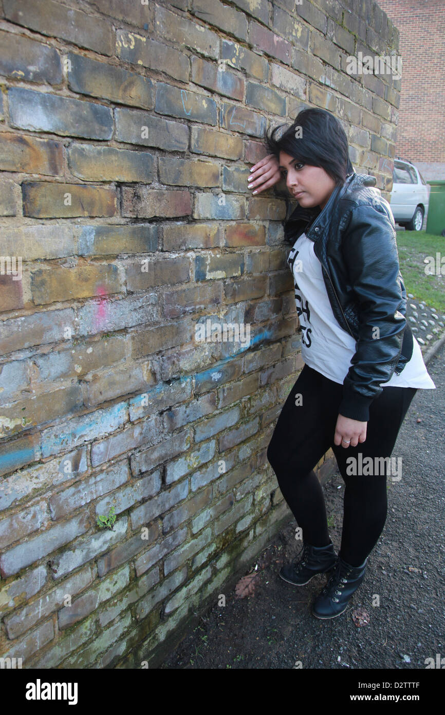 Upset and scared Asian girl leaning against a brick wall Stock Photo ...