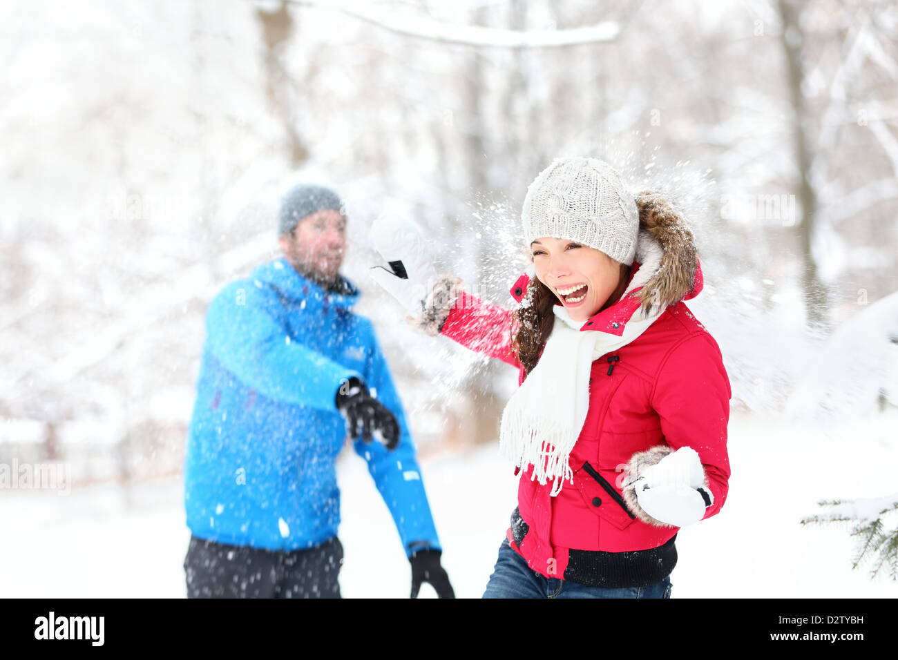 Snowball fight. Happy multi-racial winter couple having fun playing in ...
