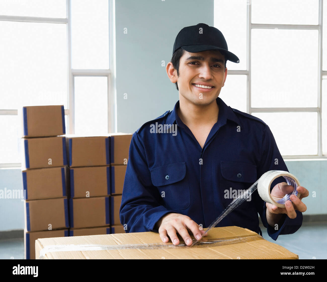 Delivery man packing cardboard box and smiling Stock Photo - Alamy