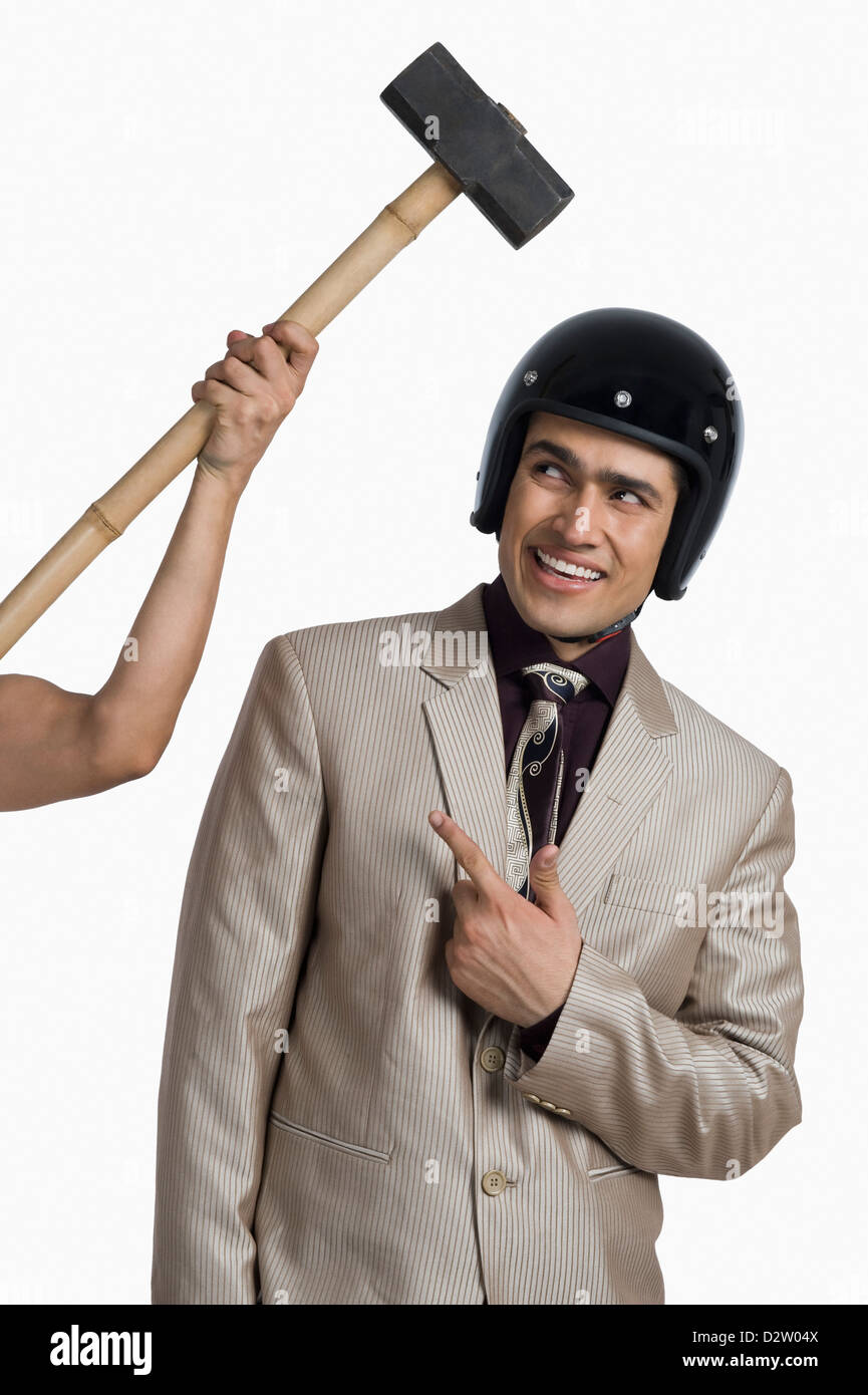 Person's hand hitting a hammer on a businessman wearing a helmet Stock ...