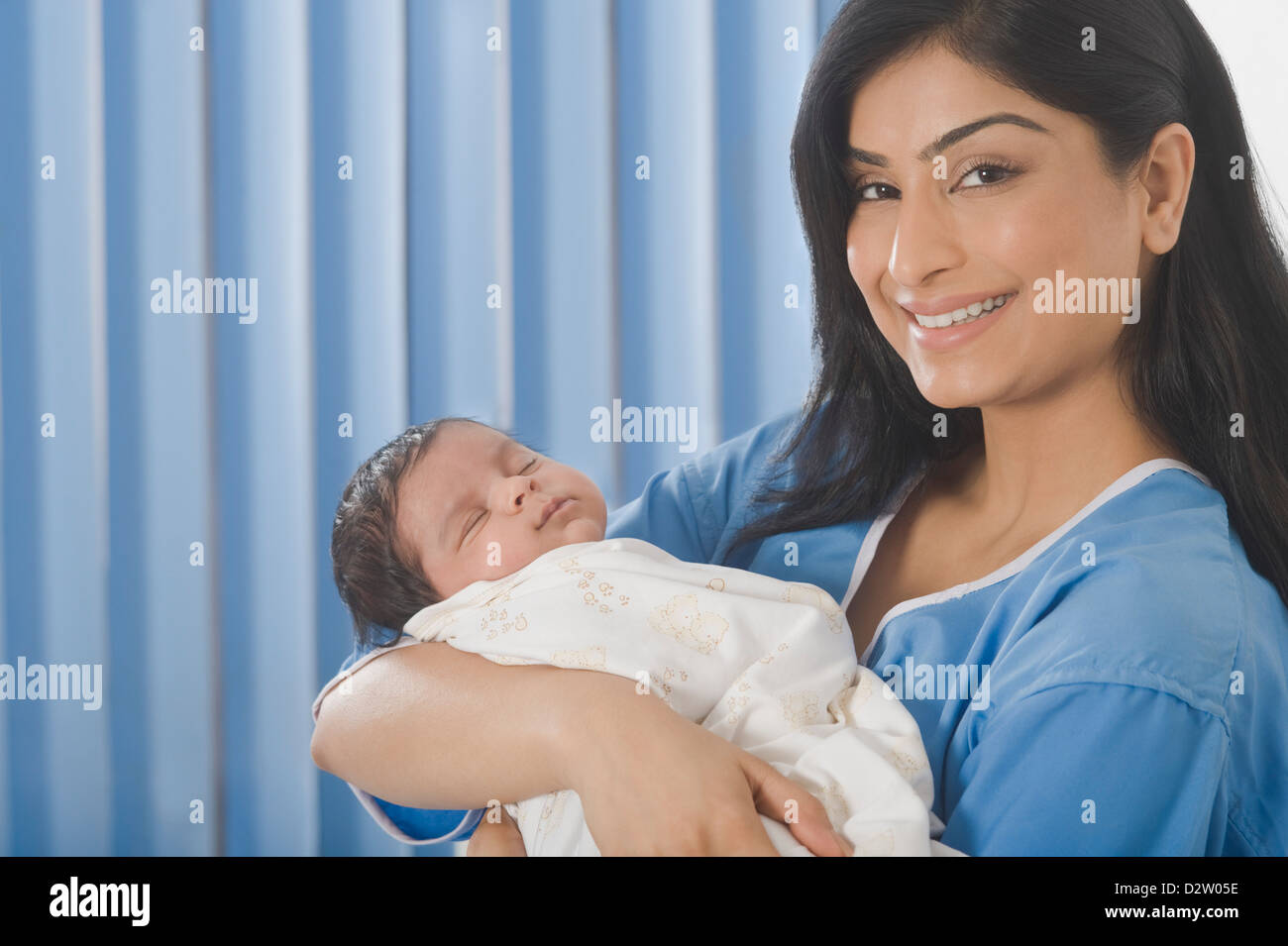 Portrait of a woman carrying her baby and smiling Stock Photo - Alamy