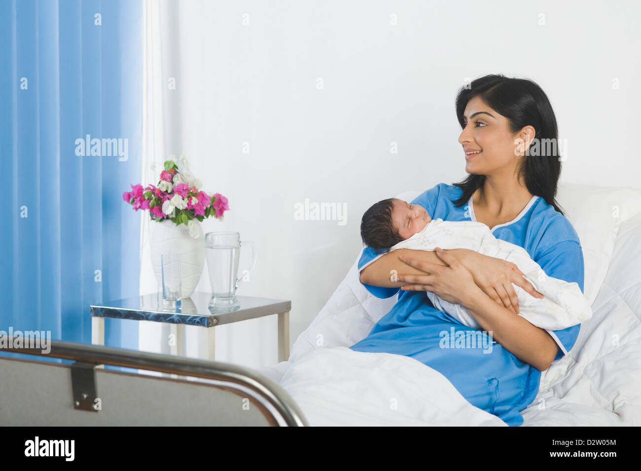 Woman carrying her baby and smiling Stock Photo - Alamy