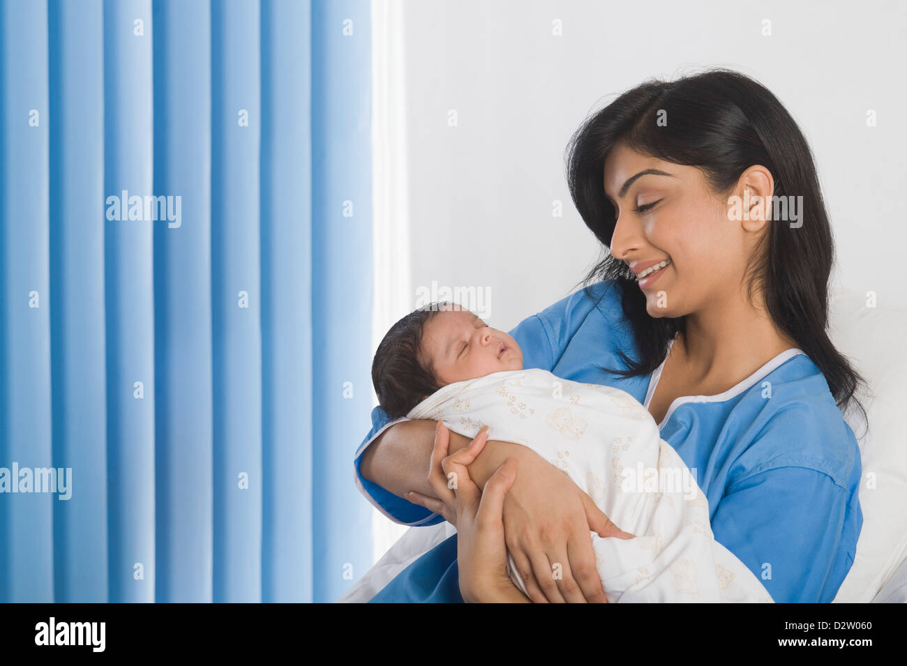 Woman carrying her baby and smiling Stock Photo - Alamy