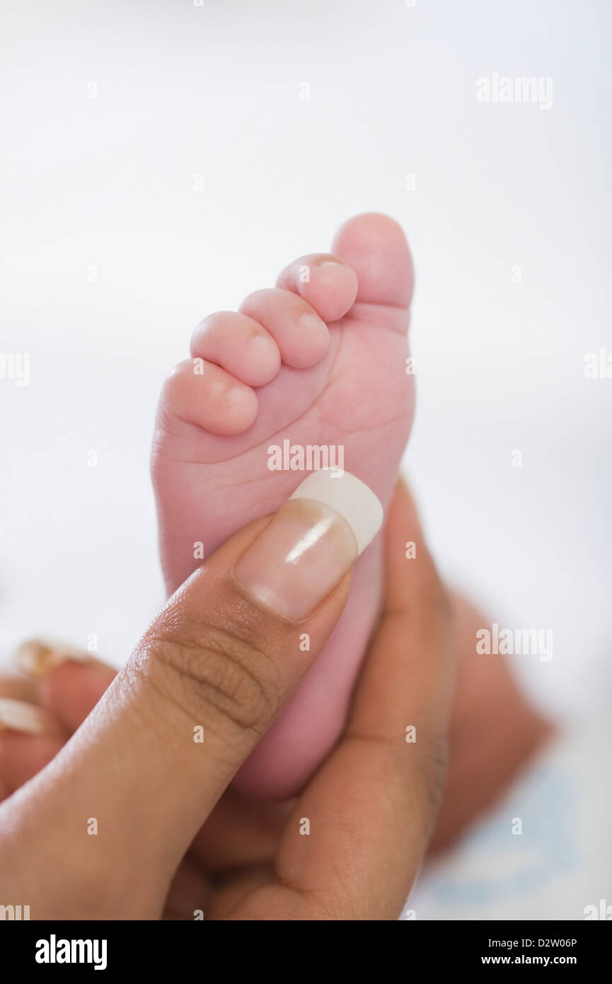 Woman's hand touching baby's feet Stock Photo - Alamy