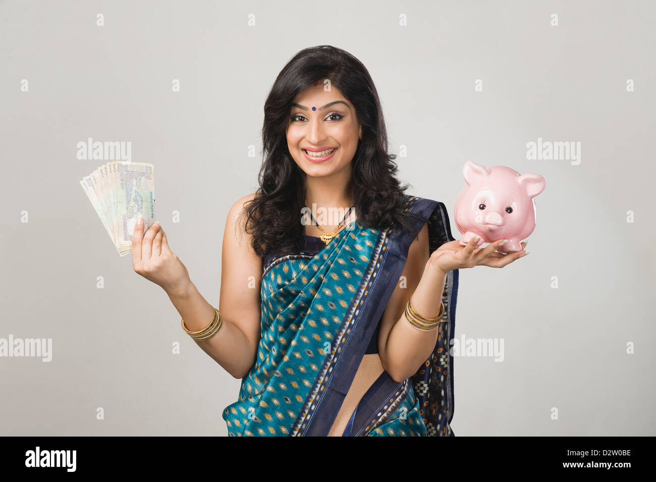 Portrait of a woman holding money and a piggybank Stock Photo - Alamy