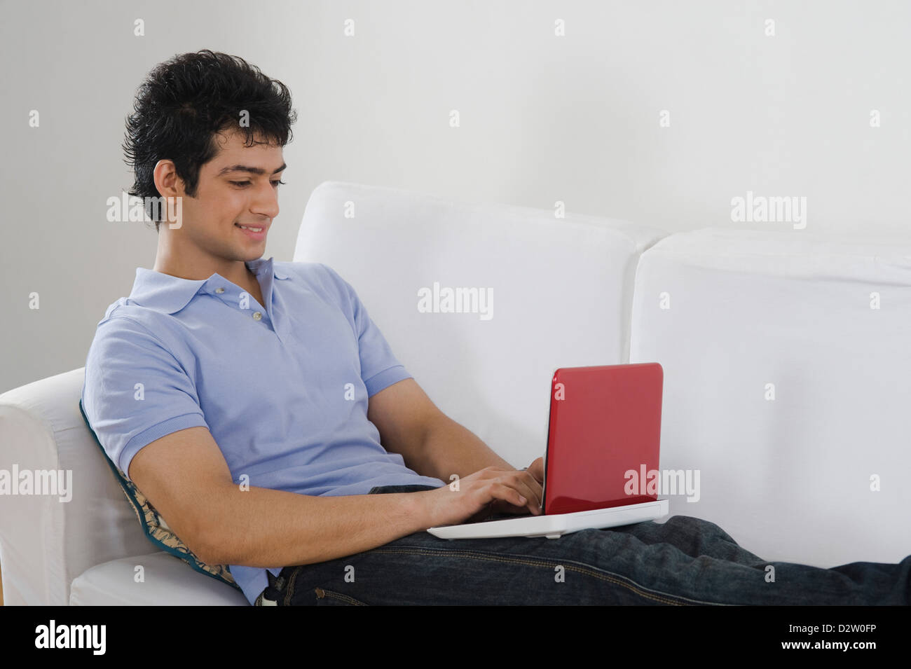 Man using a laptop on a couch Stock Photo - Alamy