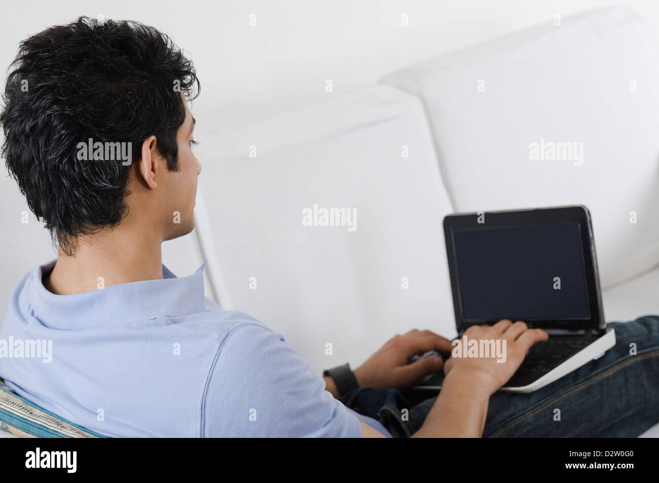 Man using a laptop on a couch Stock Photo - Alamy