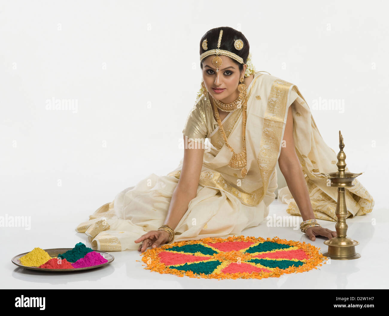 Indian woman in traditional clothing making rangoli at Durga festival ...