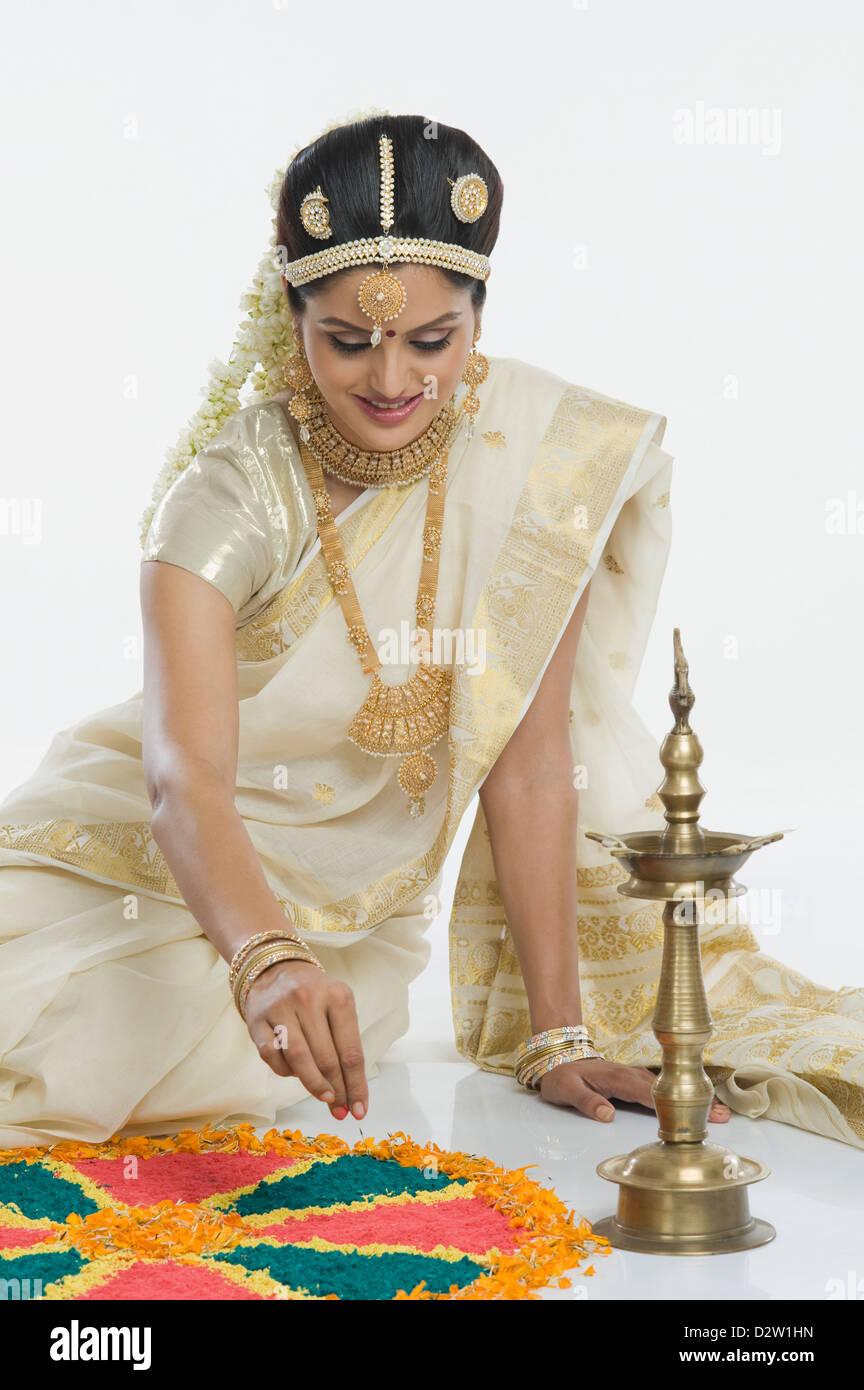 Indian woman in traditional clothing making rangoli at Durga festival ...