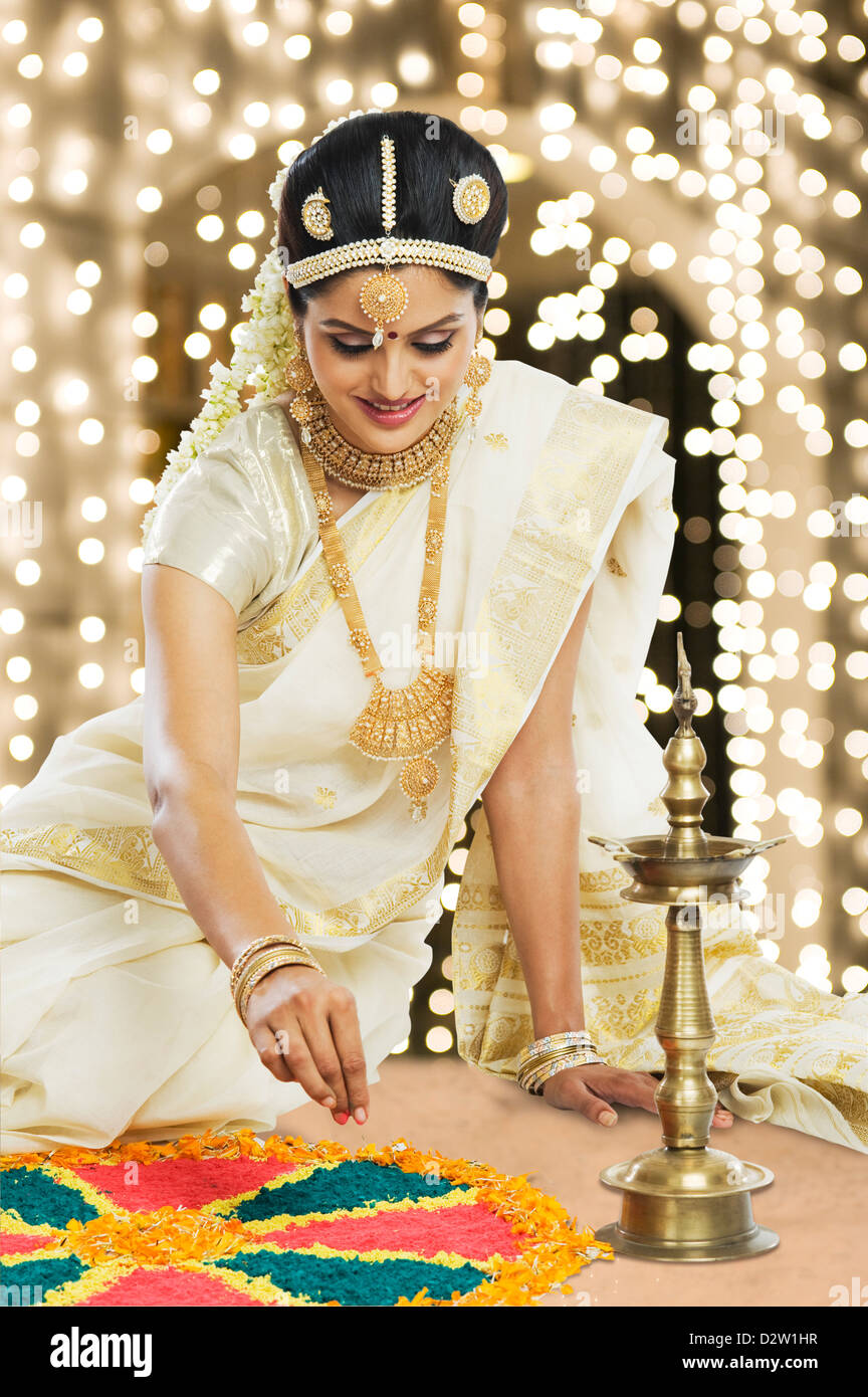 Indian woman in traditional clothing making rangoli at Durga festival ...