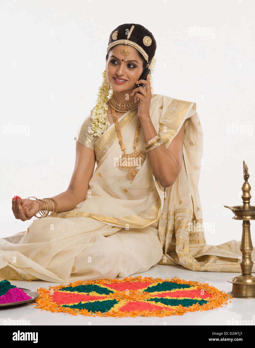 Indian woman in traditional clothing making rangoli and talking on a ...
