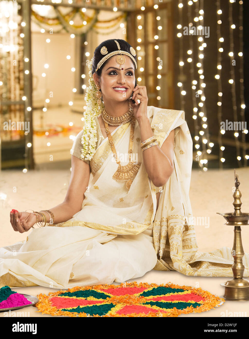 Indian woman in traditional clothing making rangoli and talking on a ...