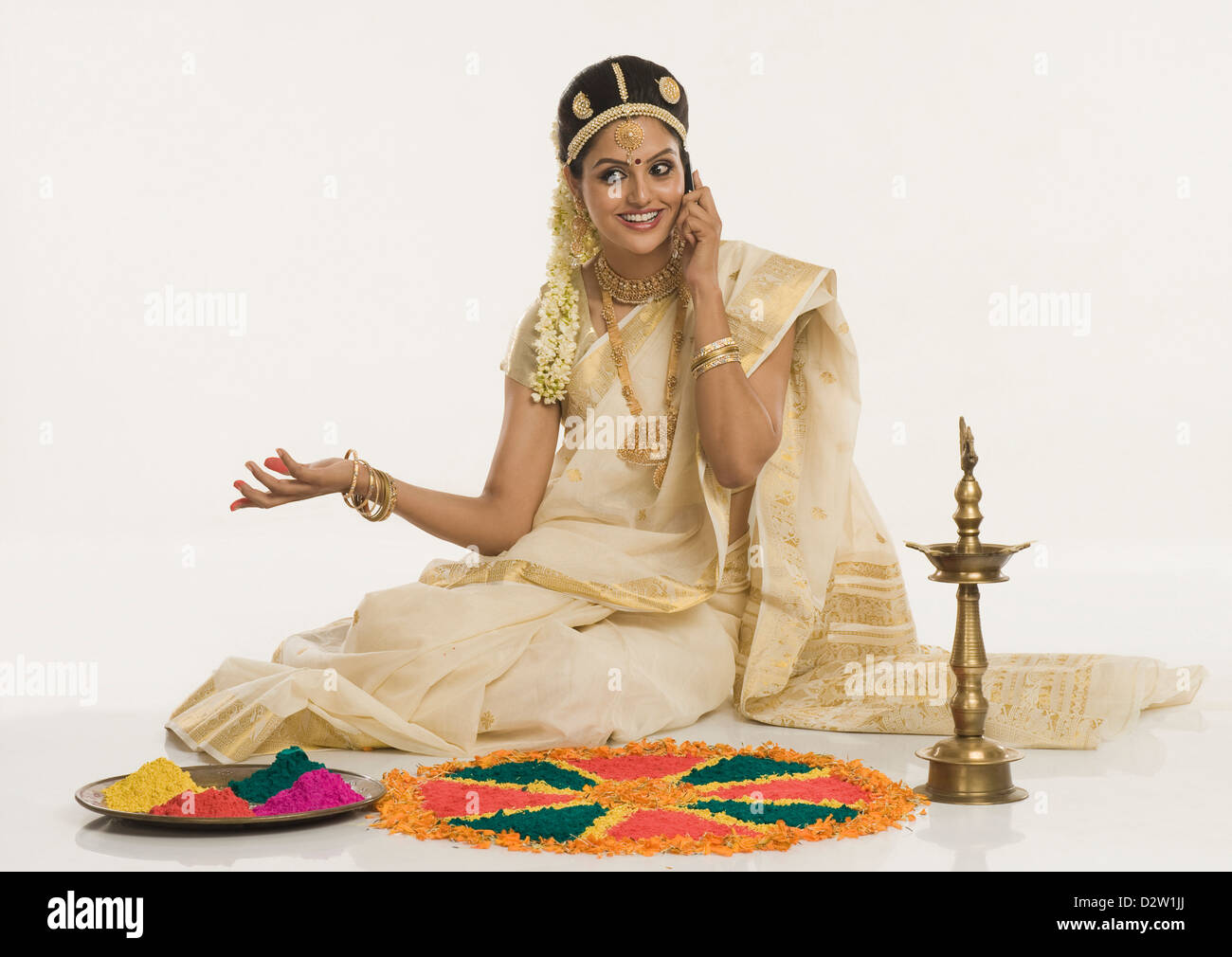 Indian woman in traditional clothing making rangoli and talking on a ...