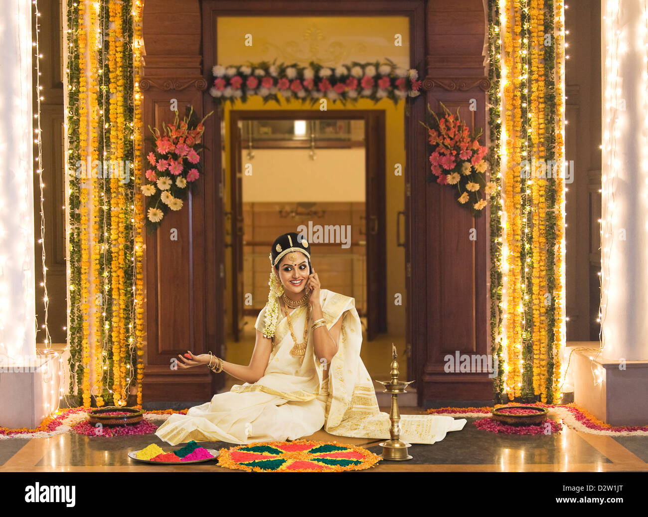Indian woman in traditional clothing making rangoli and talking on a ...