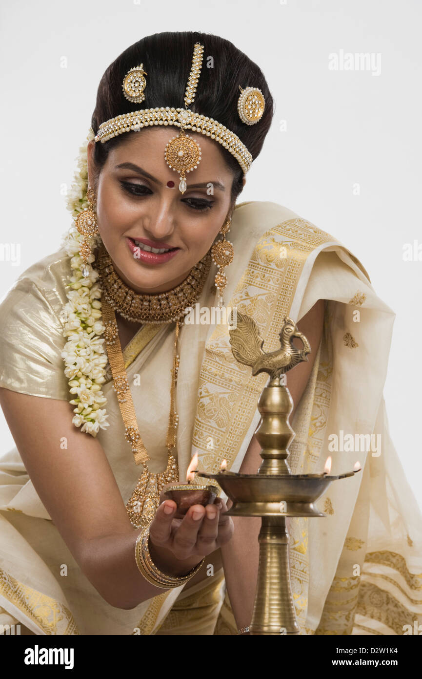 Traditional indian woman lighting diya hi-res stock photography and ...
