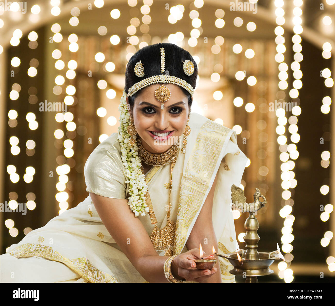 Indian woman in traditional clothing lighting an oil lamp Stock Photo ...