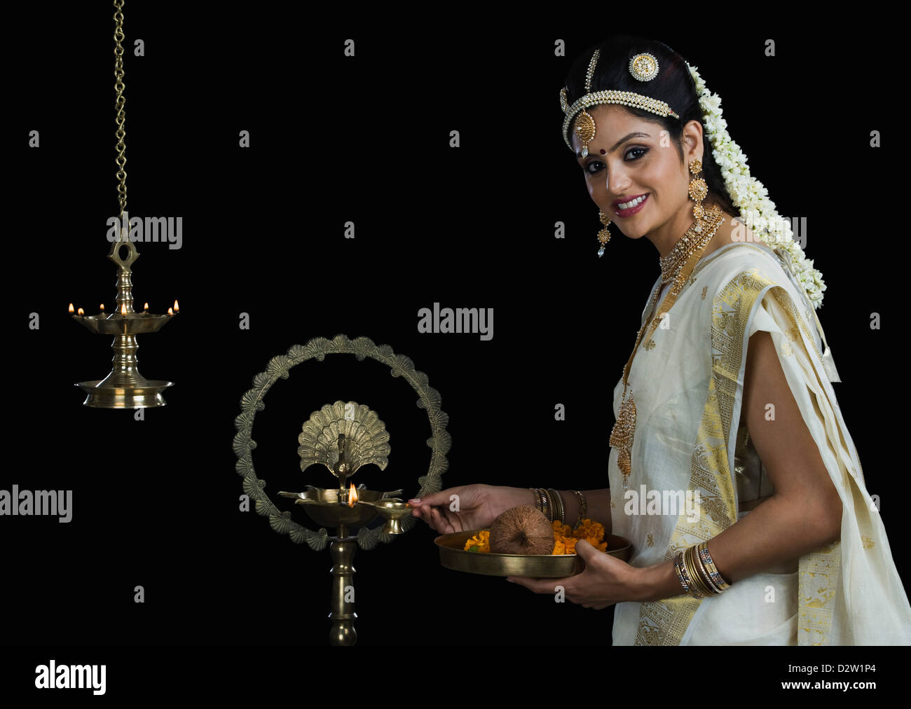 Indian woman in traditional clothing lighting an oil lamp Stock Photo ...
