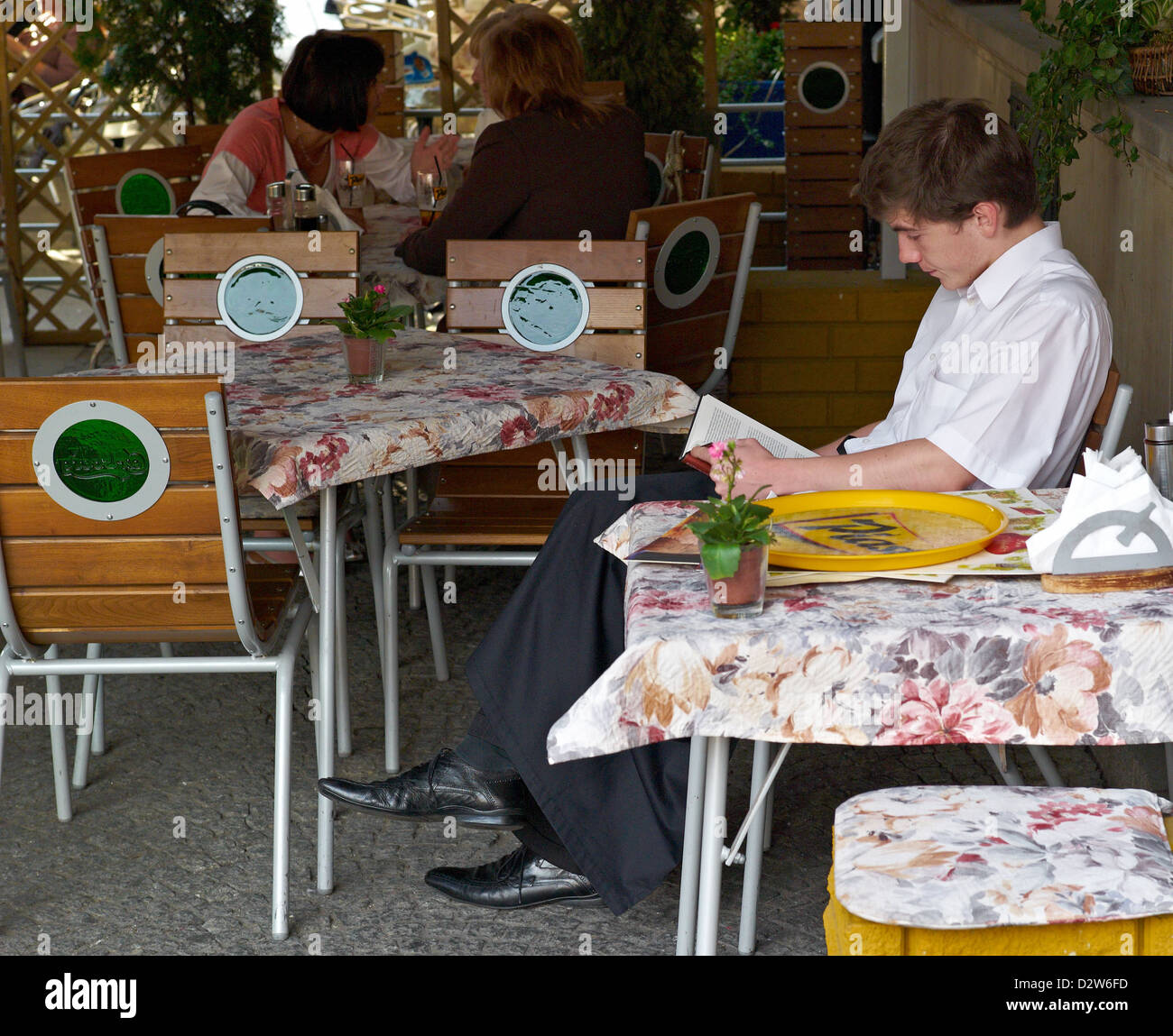 Wroclaw, Poland, a young waiter is taking a break and reading a book in ...