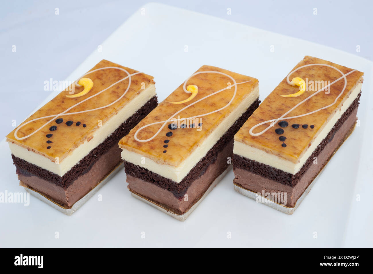 Three portion slices of chocolate sponge cake on a plate isolated on ...