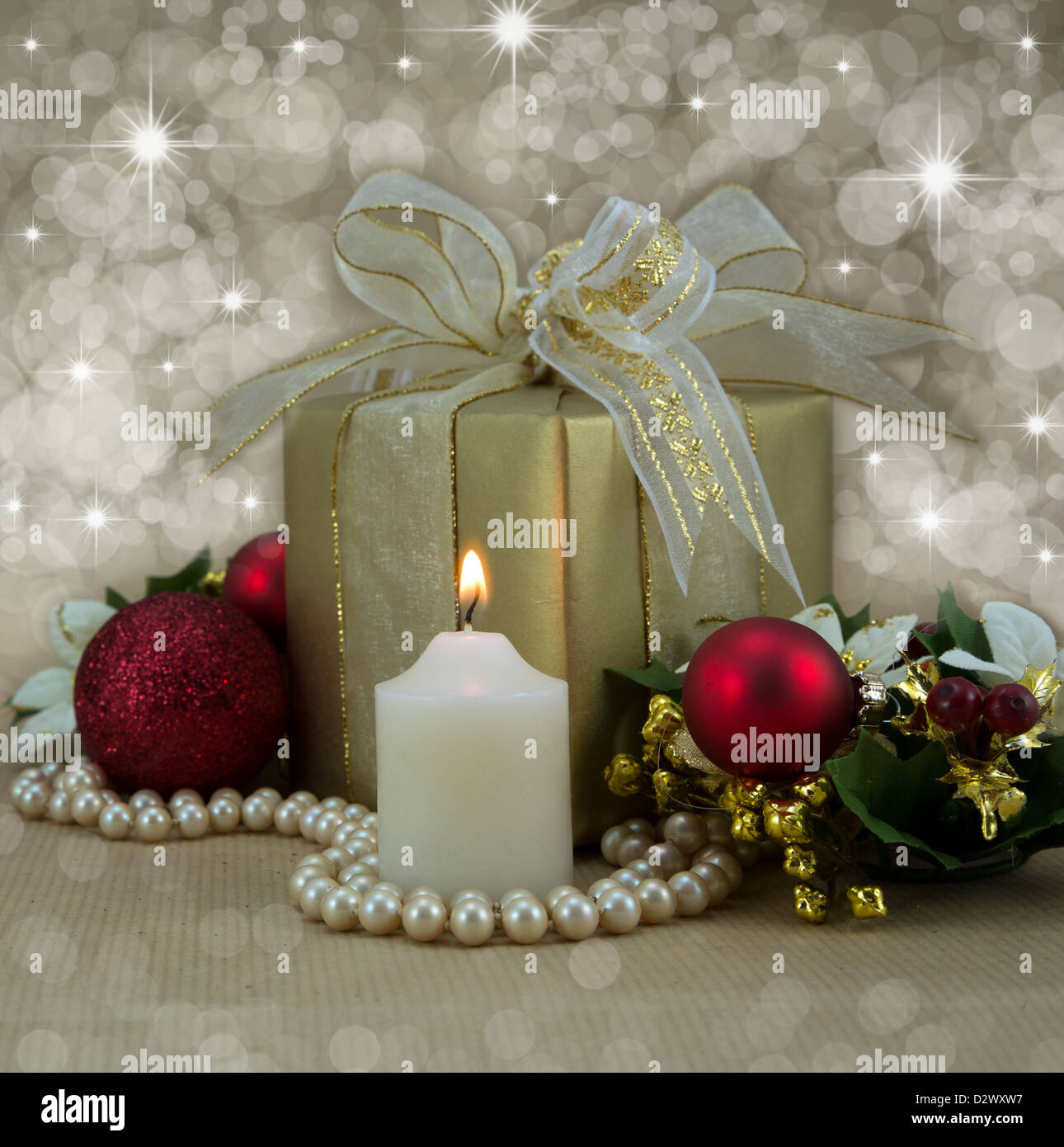 Gold wrapped present with burning candle and festive decorations Stock ...