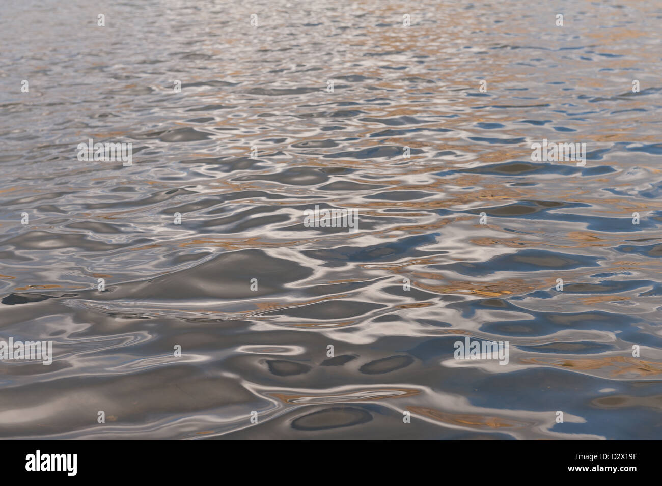Surface of a choppy lake river pond with reflected sky storm clouds and ...