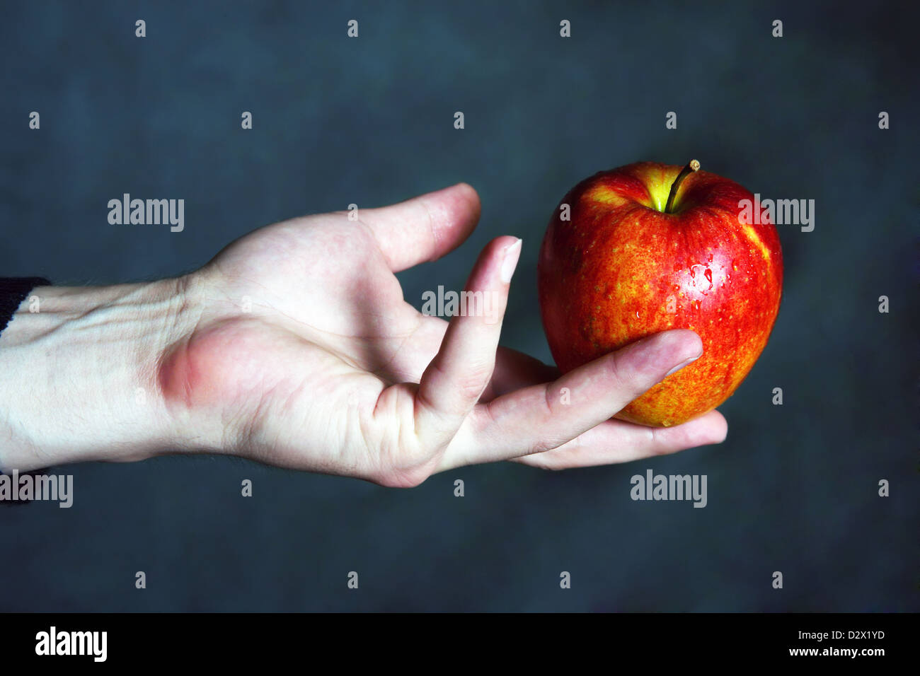 Man's hand with a red apple on a dark background Stock Photo - Alamy