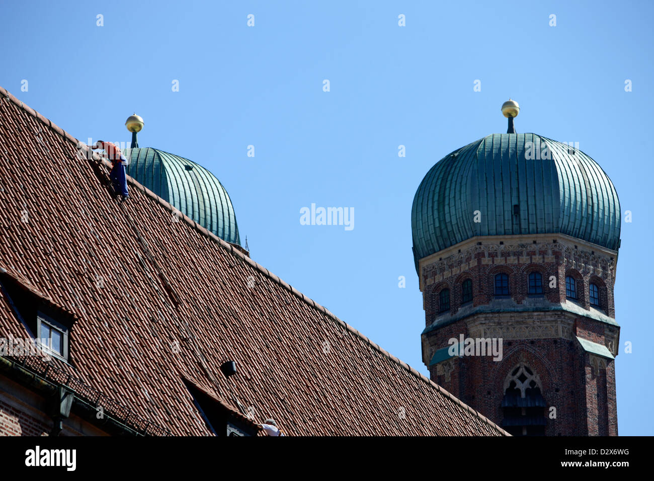 Munich, Germany, a man on a peaked roof and the towers of the ...
