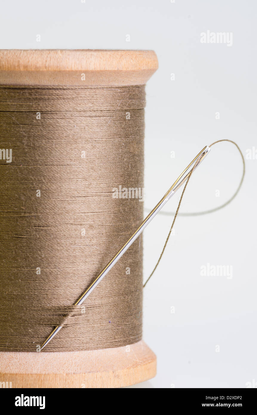 Spool of brown sewing thread with a needle Stock Photo - Alamy