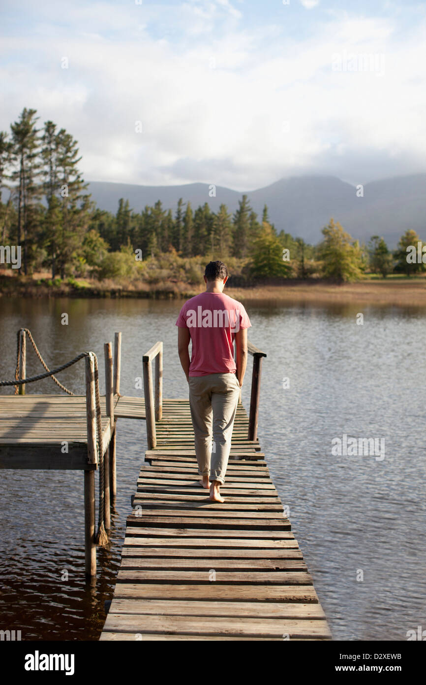 Man walking along dock over lake Stock Photo - Alamy