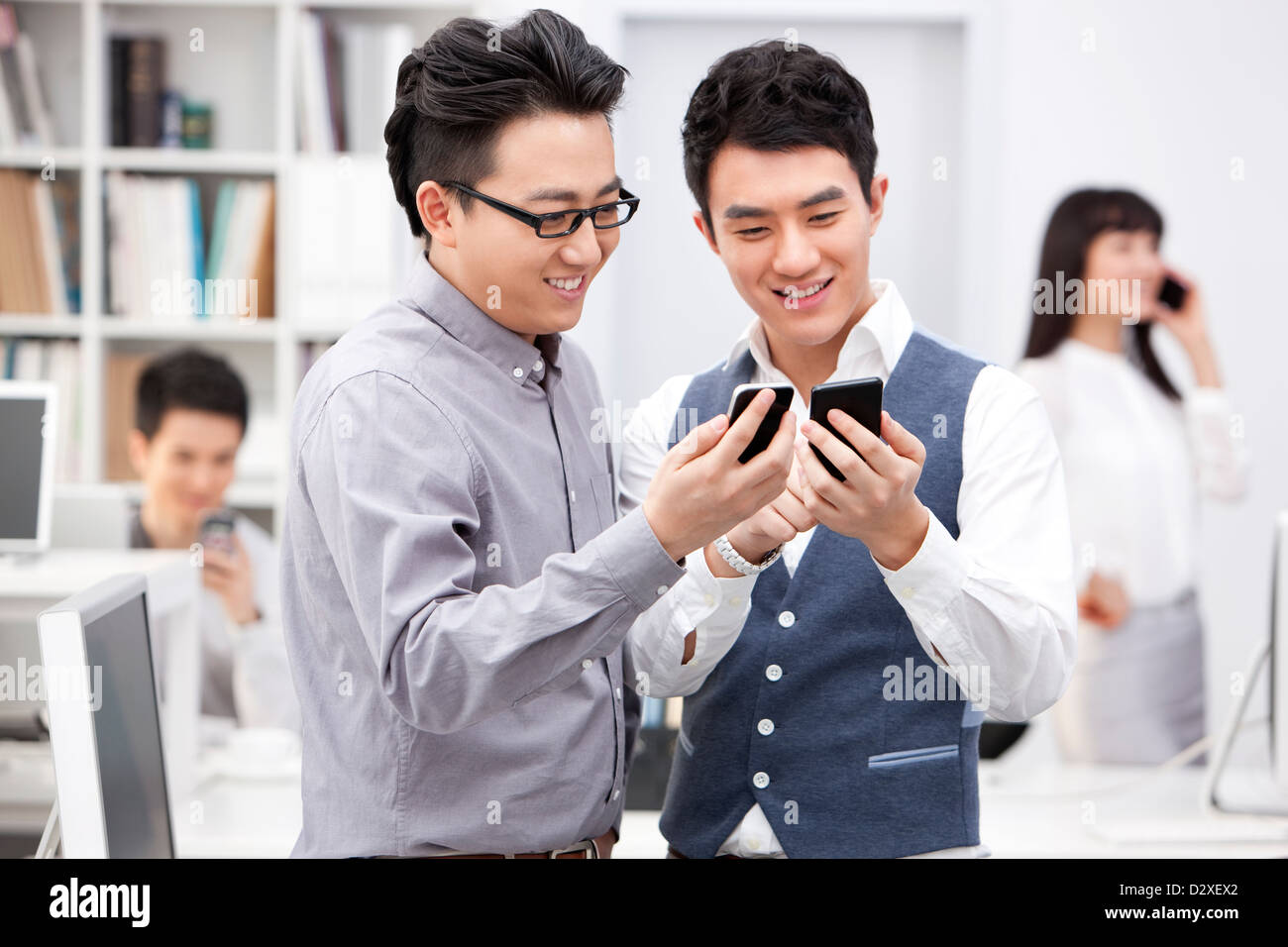 Happy business colleagues with smart phones in the office Stock Photo ...