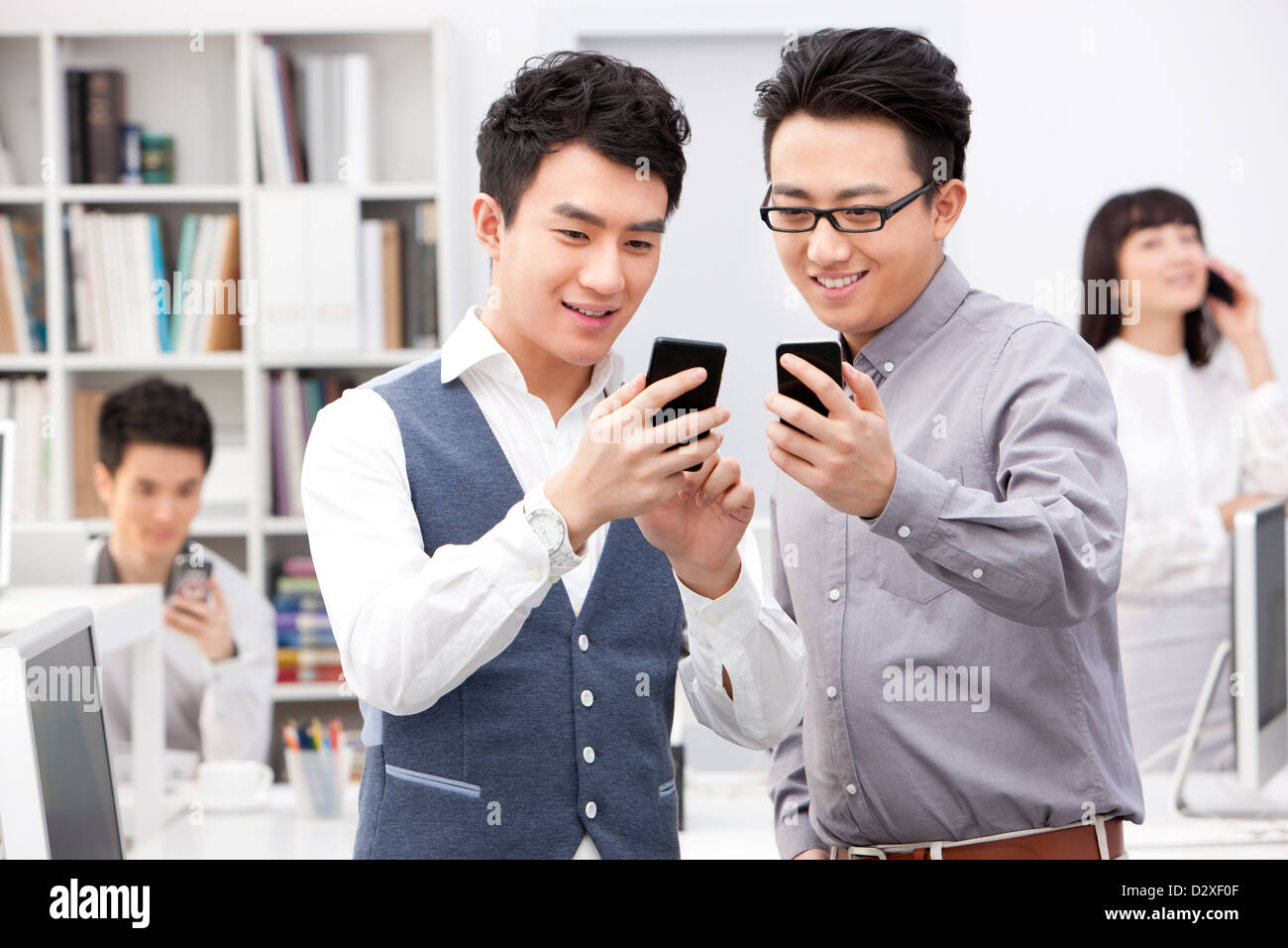 Happy business colleagues with smart phones in the office Stock Photo ...