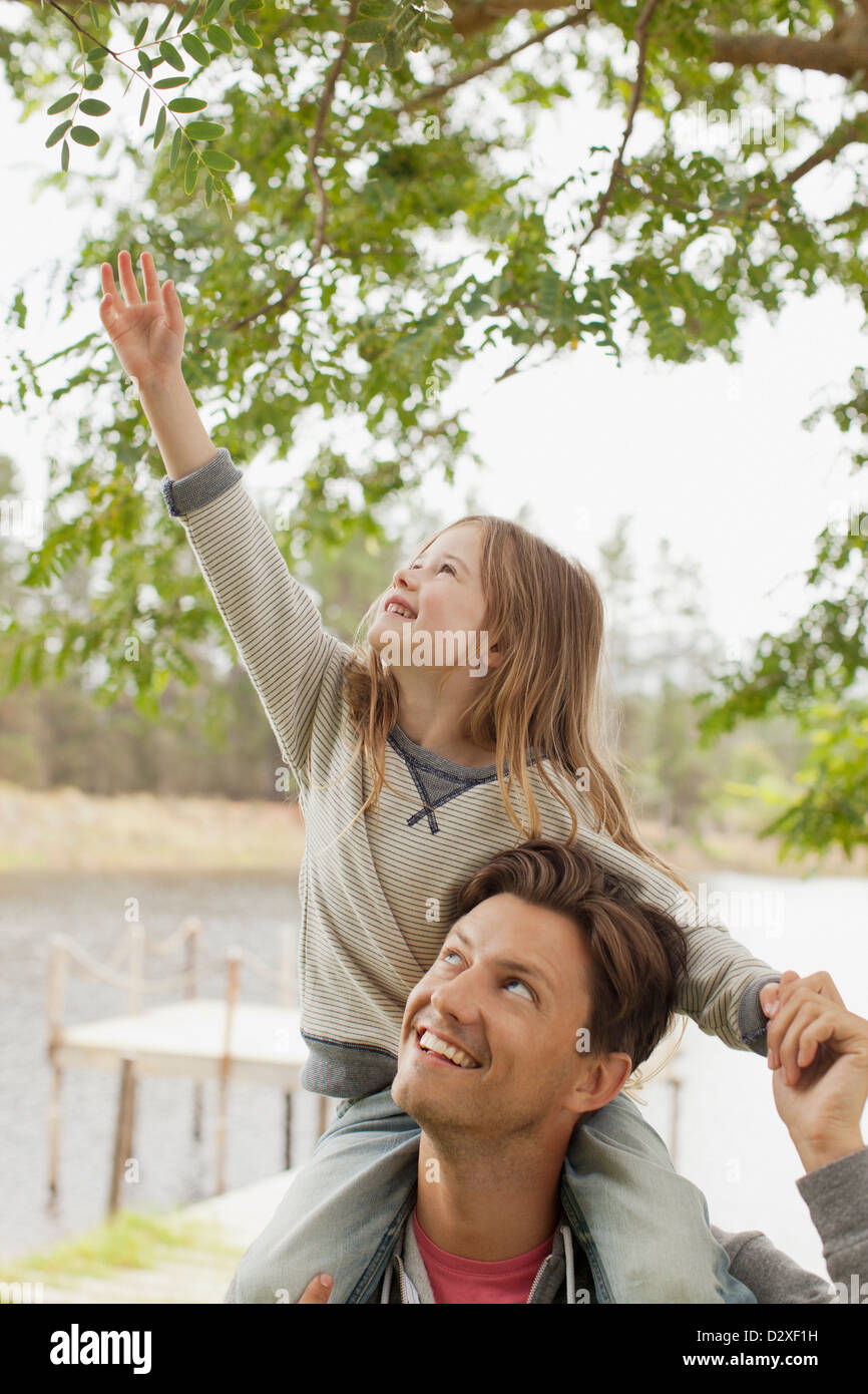 Daughter on father’s shoulders reaching for branch Stock Photo - Alamy