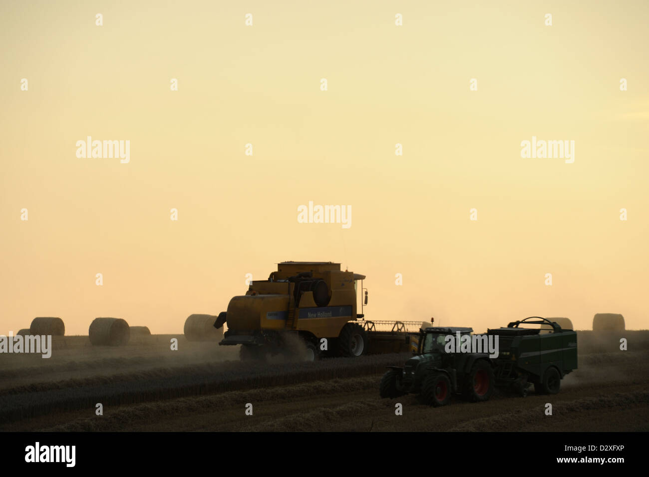 A combine harvester working in fields at sunset Stock Photo - Alamy