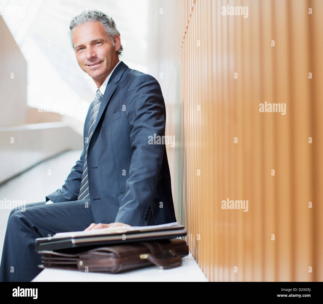 Portrait of smiling businessman with laptop and briefcase Stock Photo ...
