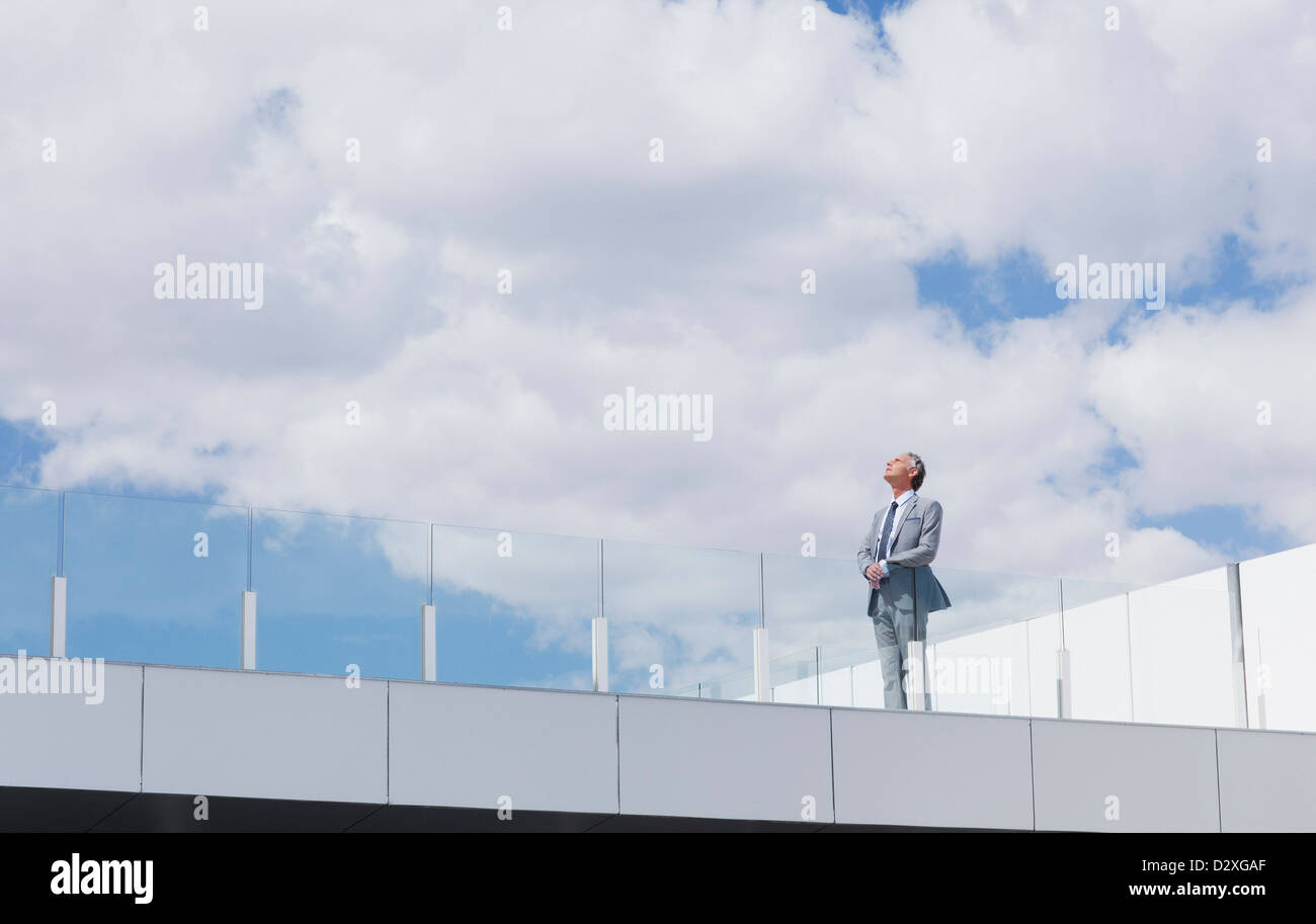 Pensive businessman looking up at sky on rooftop balcony Stock Photo ...