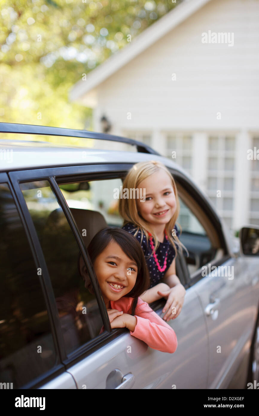Girls smiling out car window Stock Photo - Alamy