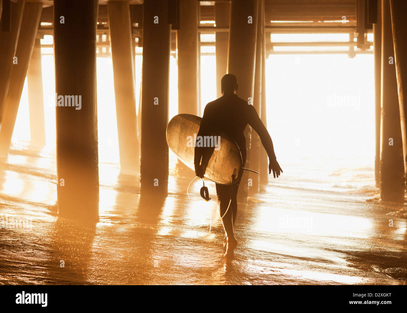 Older surfer carrying board under pier Stock Photo - Alamy