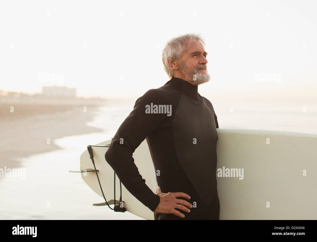 Older surfer carrying board on beach Stock Photo - Alamy
