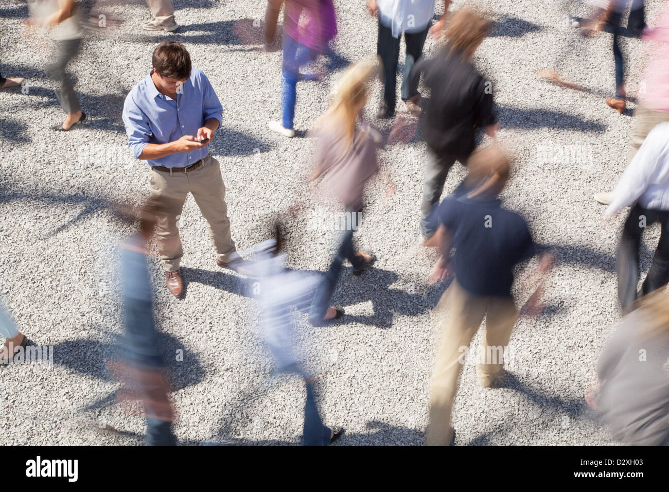 Man checking cell phone among rushing crowd Stock Photo - Alamy