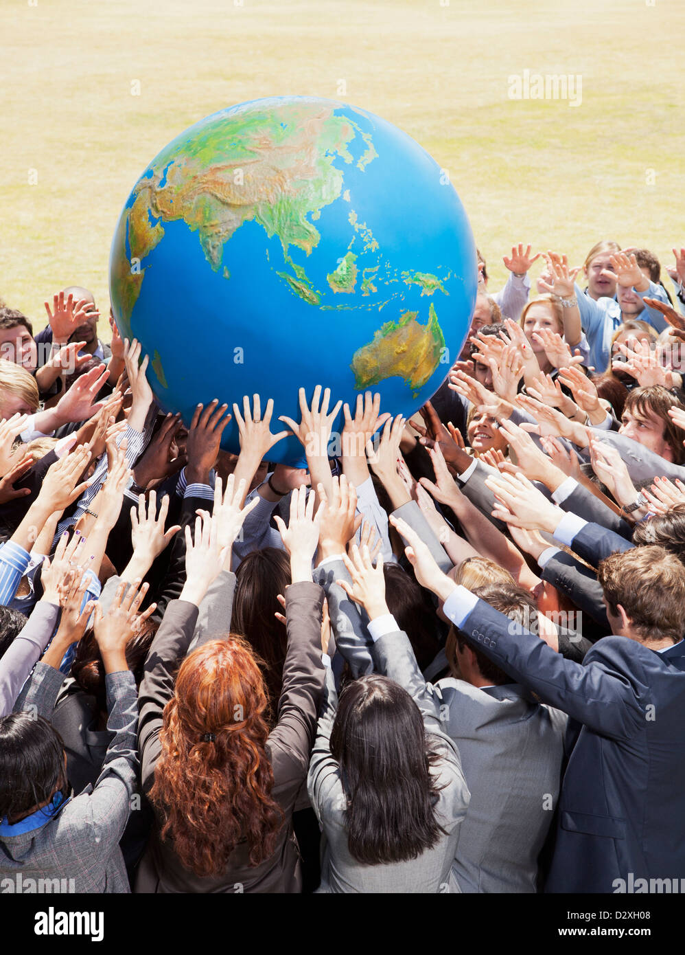 Crowd of business people reaching for globe Stock Photo - Alamy