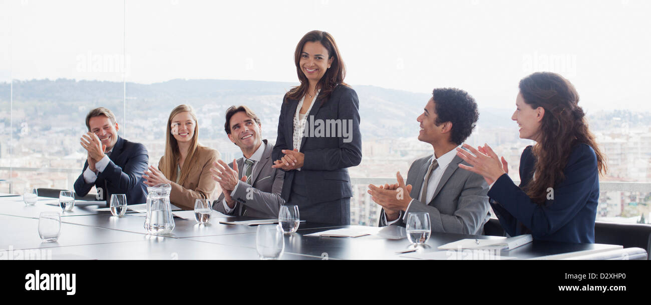 Co-workers clapping for businesswoman in conference room Stock Photo ...