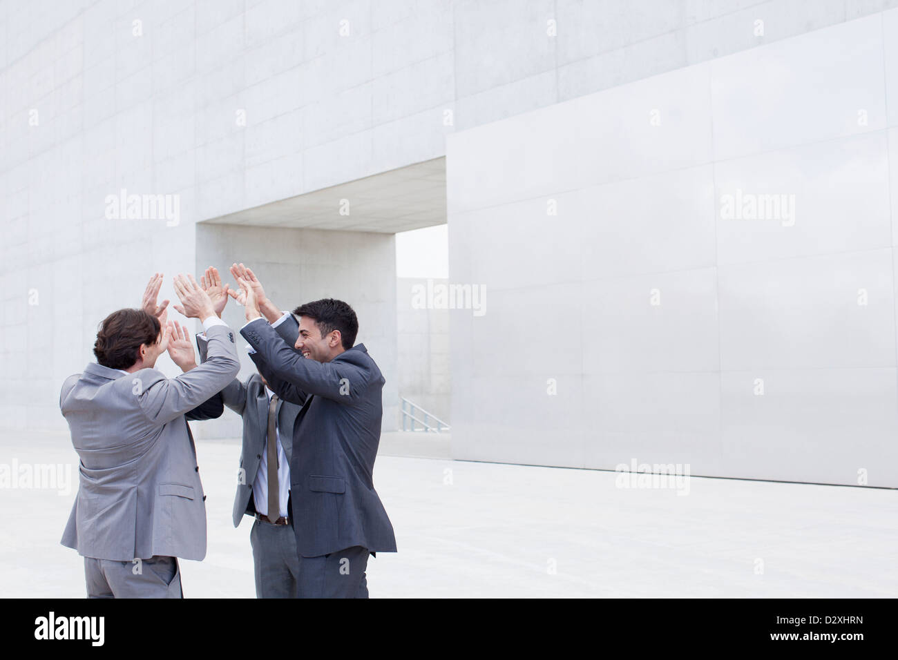 Business people high-fiving outside cultural center Stock Photo - Alamy