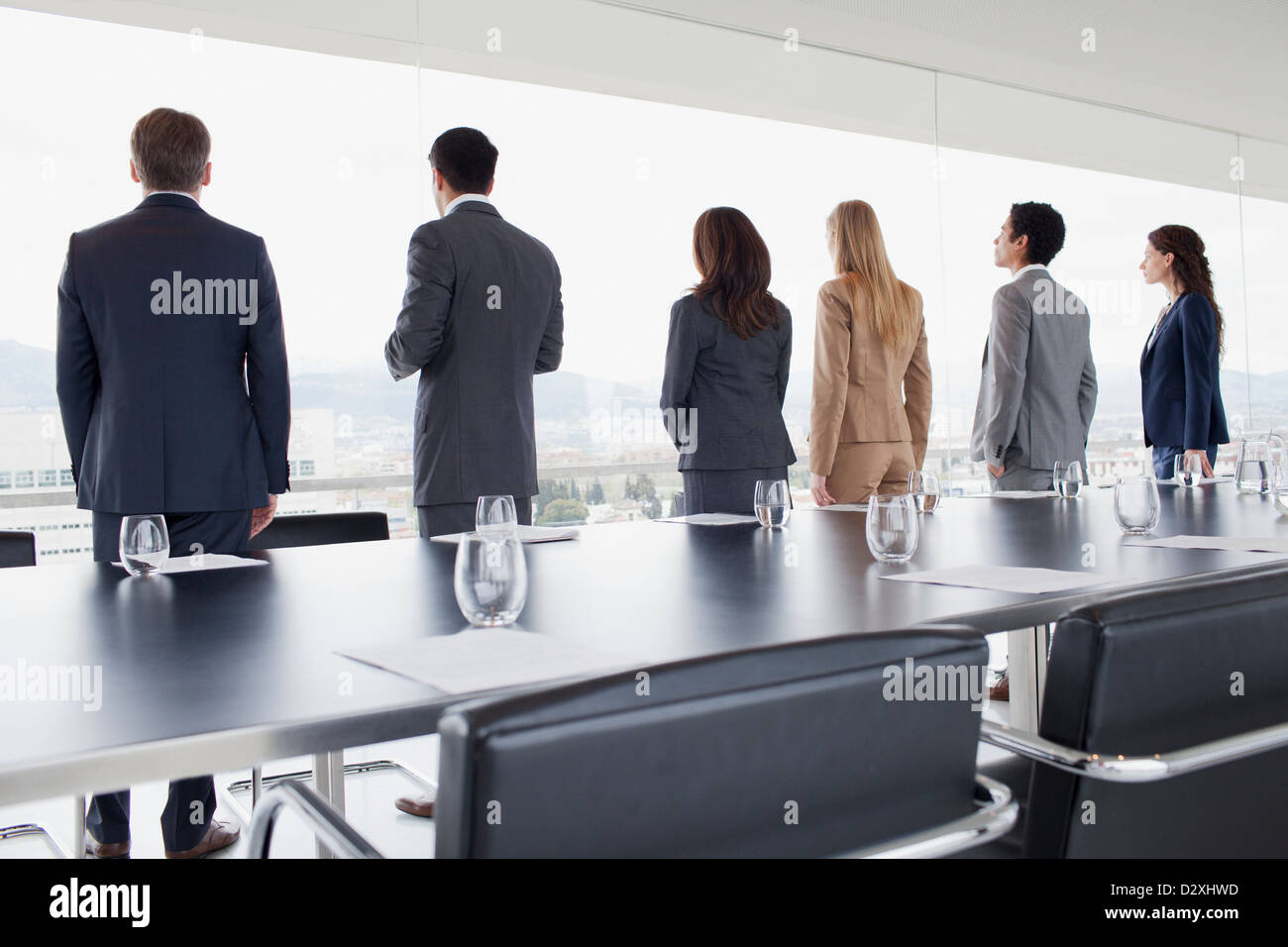 Business people in a row looking out conference room window Stock Photo ...